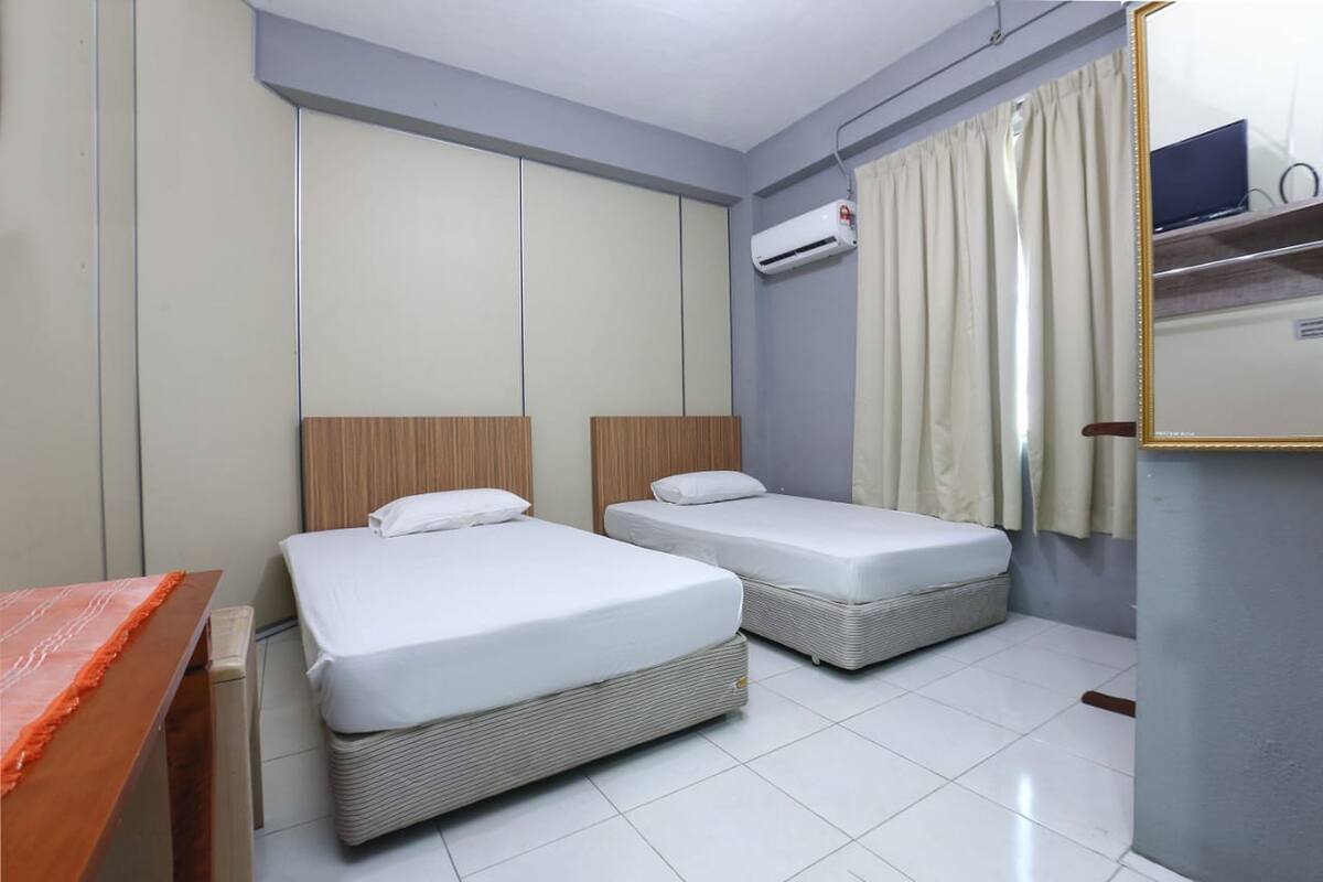 Quarto com duas camas, uma escrivaninha, ar condicionado e um espelho.