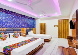 Quarto de hotel com duas camas, parede estampada, móveis de madeira e ventiladores de teto.