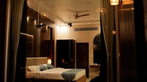 Quarto moderno com cama grande, ventilador de teto e vista para o horizonte urbano pela janela.