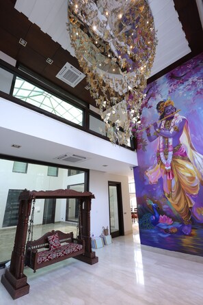 Interior em vários níveis com uma rede, um lustre decorativo e um mural de uma divindade.