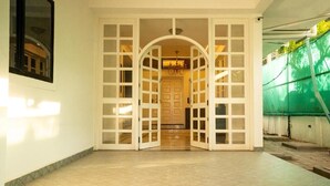 Corredor com piso ladrilhado e portas brancas com painéis de vidro.
