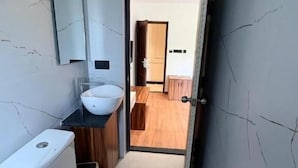 Casa de banho pequena com sanita, lavatório e espelho na parede.