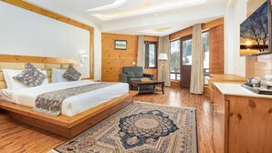 Quarto de hotel com uma cama grande, uma mesa, uma cadeira e vista para o exterior.
