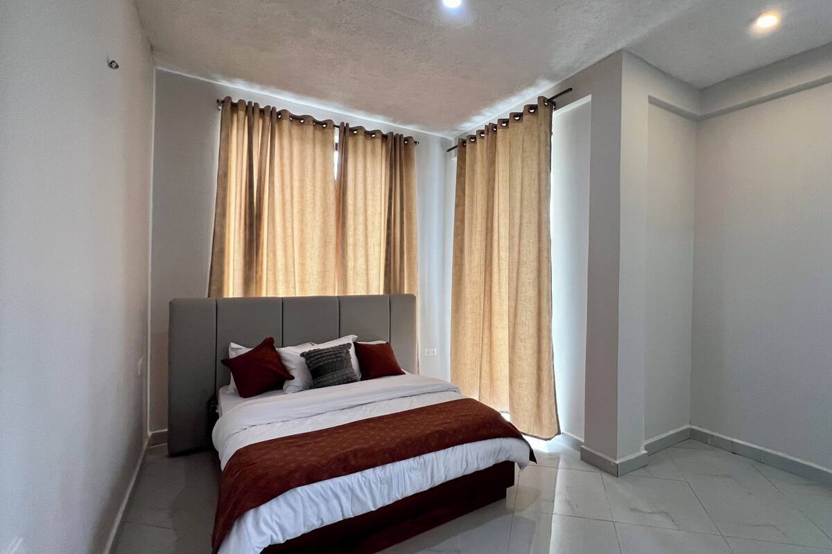 Um quarto com cama, cortinas e janela.
