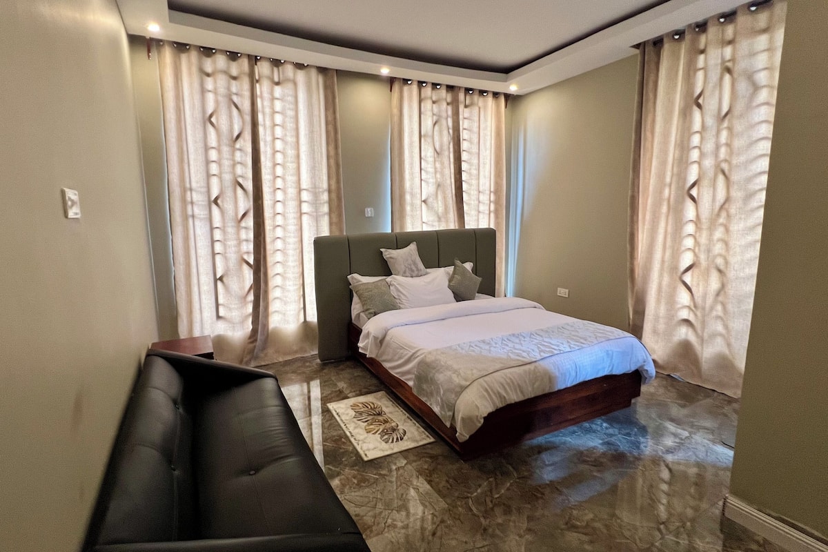 Quarto moderno com cama, um banco e cortinas.