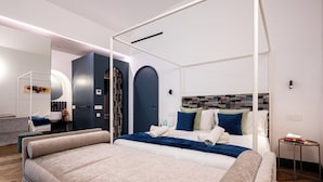 Quarto de hotel moderno com cama de dossel, um espelho grande, guarda-roupa embutido e uma pequena mesa de apoio.