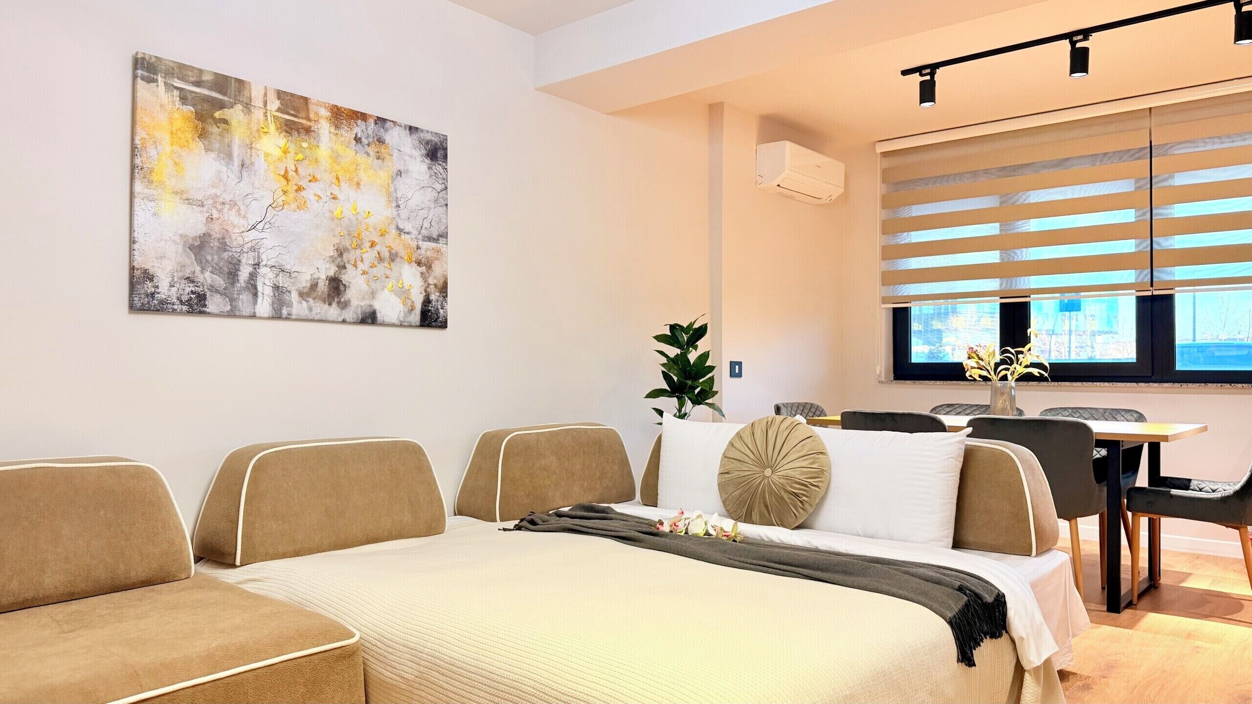 Quarto de hotel moderno com cama, área de estar e uma janela grande.