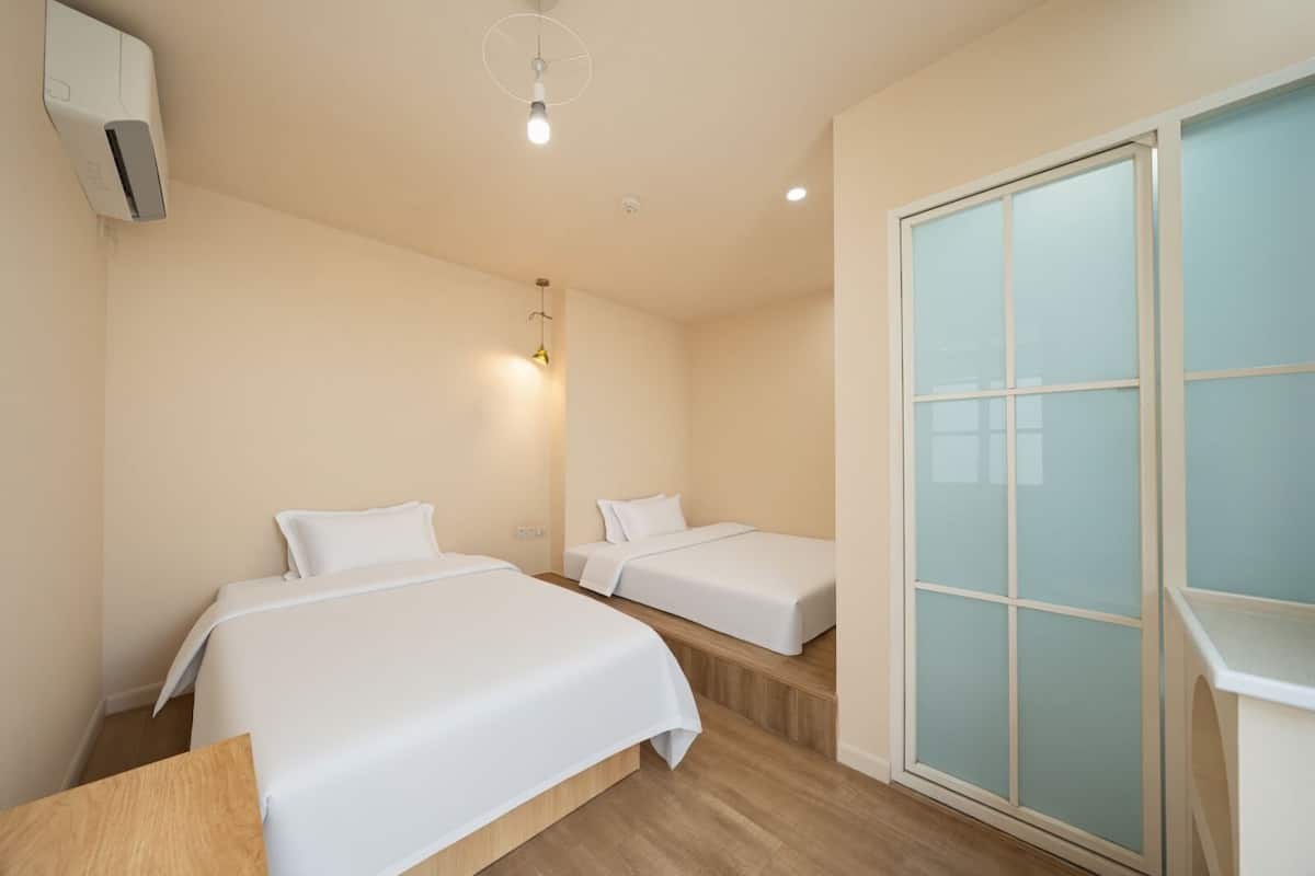 Quarto de hotel com duas camas, um guarda-roupa e uma lâmpada no teto.