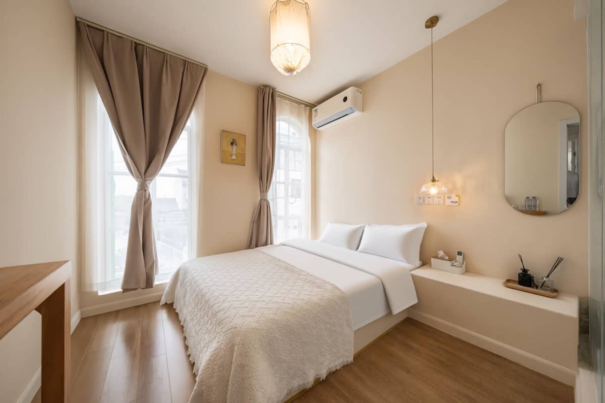 Quarto de hotel com cama, mesa de cabeceira, ar condicionado e espelho.