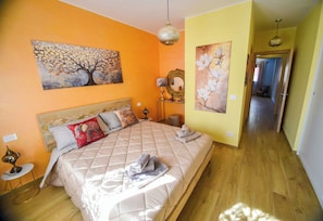 Quarto com cama, mesa de cabeceira, abajur e obras de arte nas paredes.