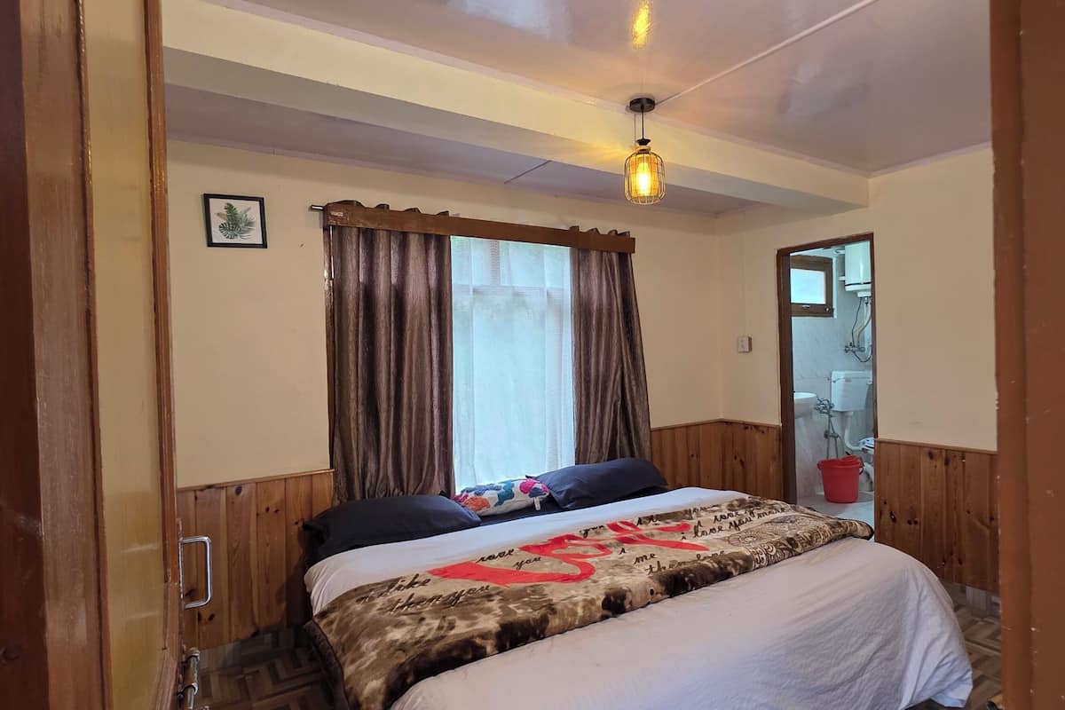 Quarto com cama, cortinas, luminária pendente, porta de madeira e espelho.