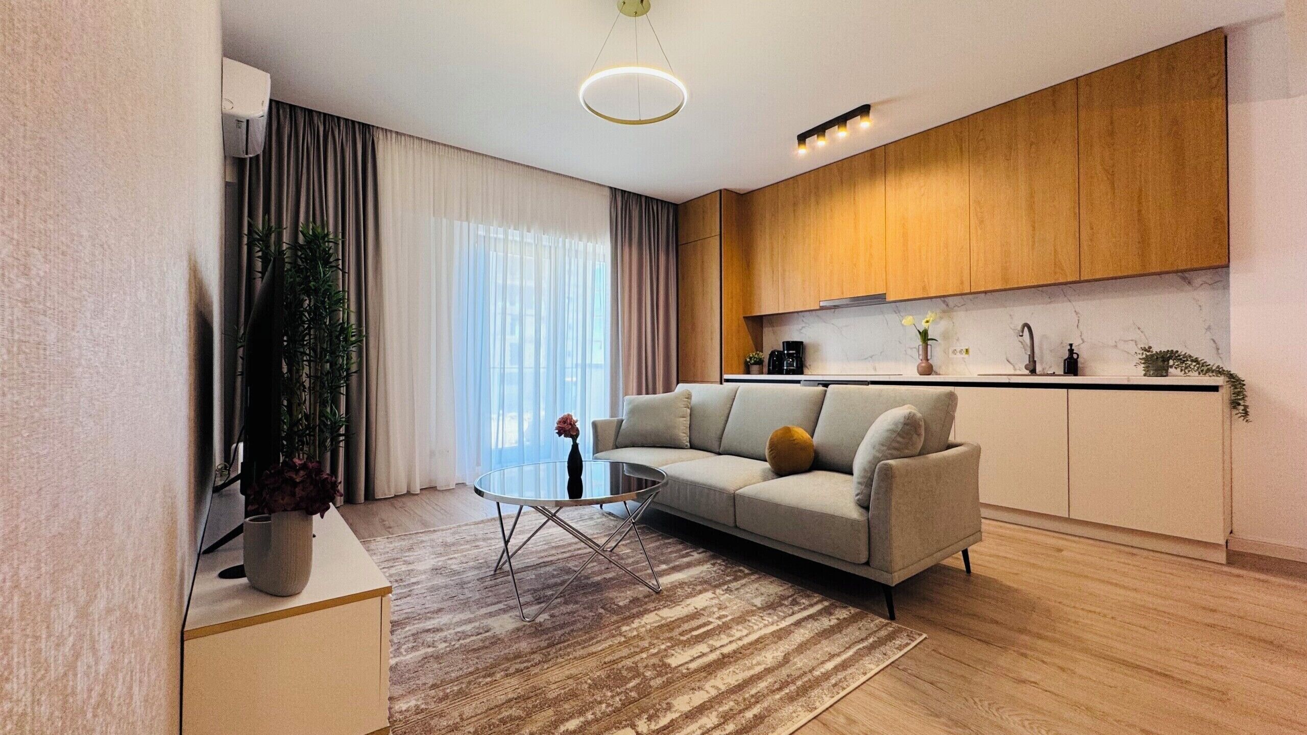 Uma sala de estar moderna com um sofá, mesa de centro e uma janela grande com cortinas.