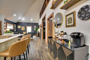 Uma cozinha moderna com cafeteira, banquetas de bar e uma área de refeições com cadeiras.