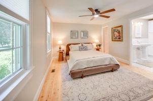 Quarto com cama, mesas de cabeceira, ventilador de teto e janela.