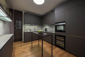 Uma cozinha moderna com armários escuros, uma ilha central e forno embutido.