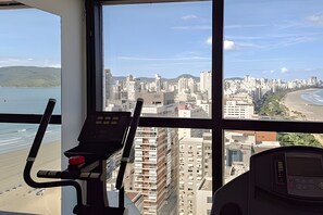 Uma academia com equipamentos de ginástica e uma janela ampla que oferece vista para a cidade.