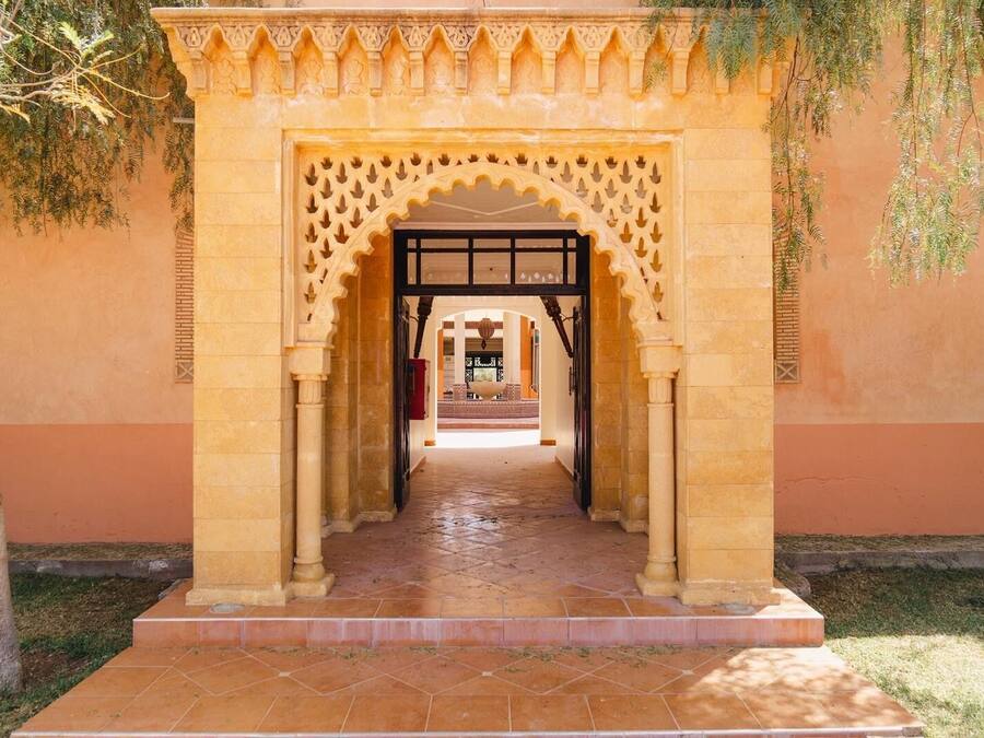 Uma entrada arqueada com um caminho de azulejos que leva a um edifício.