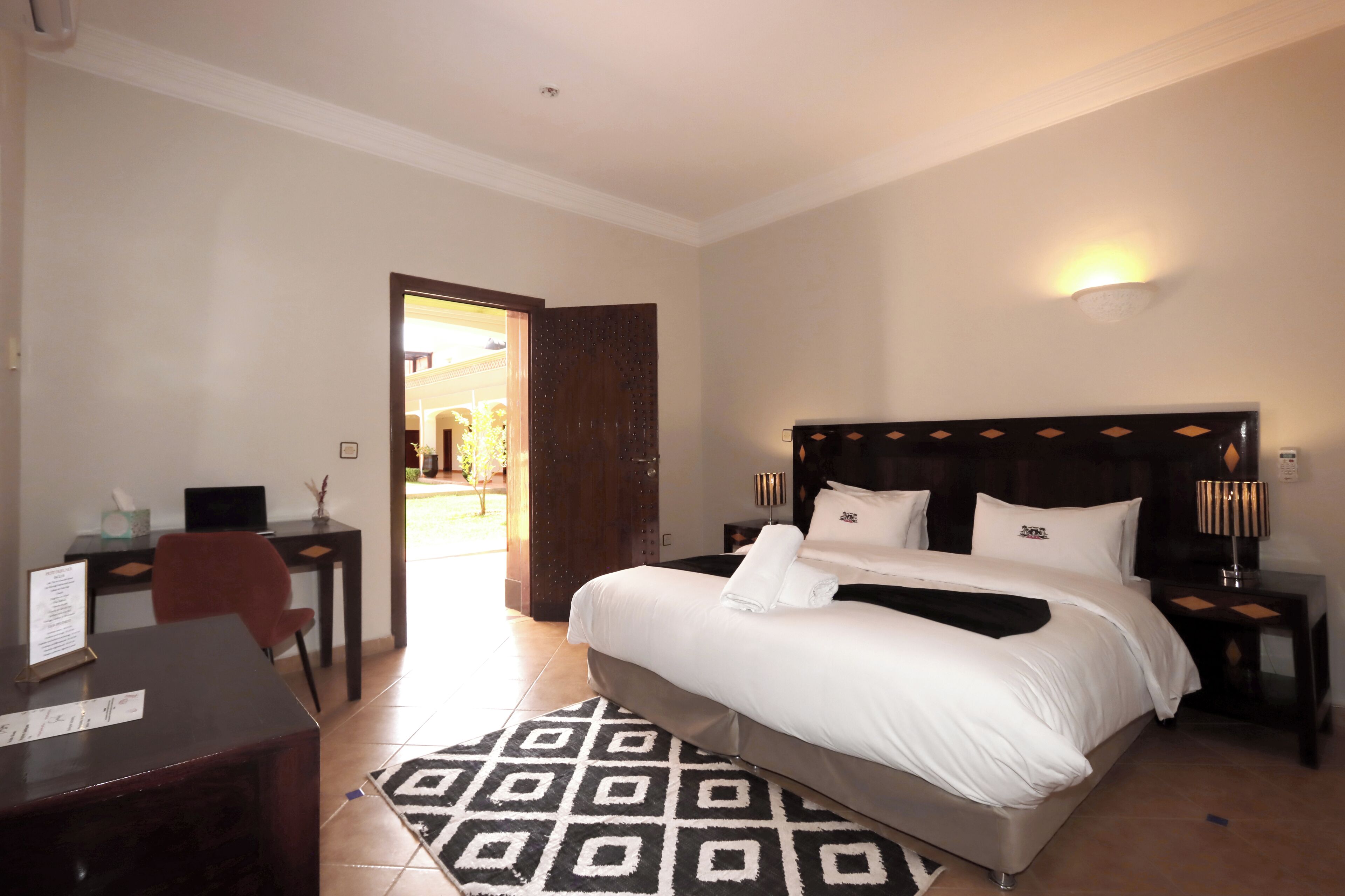 Quarto de hotel com cama, mesas de cabeceira, escrivaninha e uma cadeira.