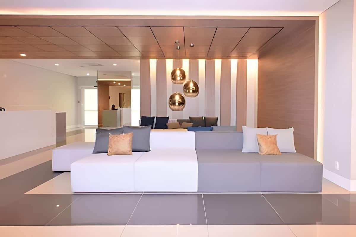 Uma sala de estar moderna com sofá seccional, iluminação pendente e vista para a área de jantar adjacente.