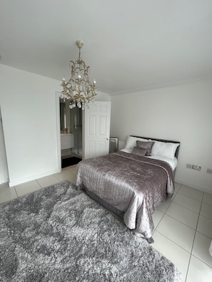 Quarto com cama, lustre, espelho e porta.
