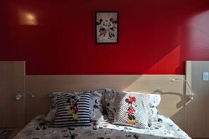 Quarto com parede vermelha, quadro e roupa de cama com tema do Mickey Mouse.