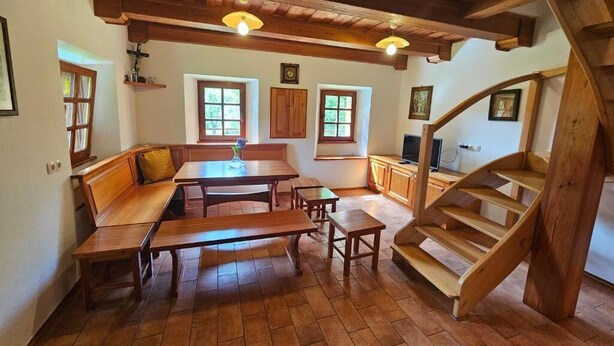Uma zona de refeições de madeira com bancos e uma mesa, uma escada e uma janela com vista.