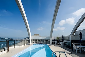 Piscina no terraço com vista para o oceano e o horizonte da cidade.