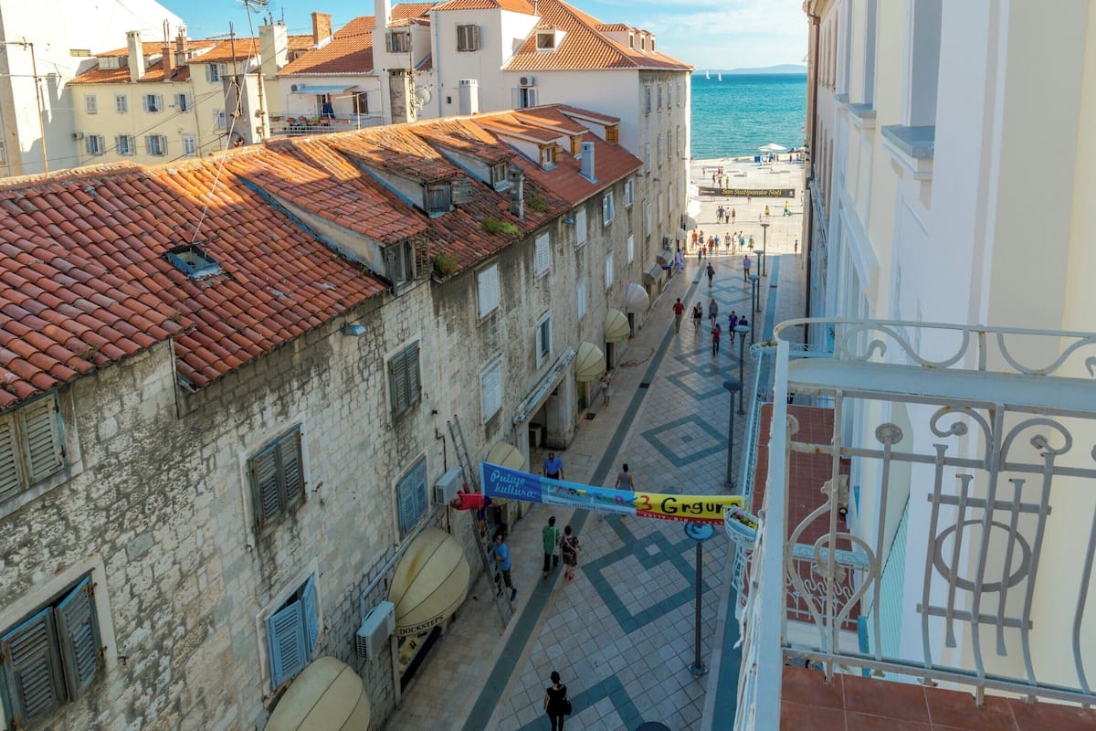 Vista da rua com prédios, um telhado telhado e céu claro.