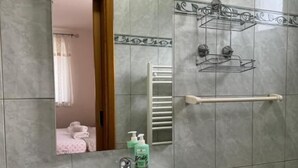 Um banheiro com pia branca, espelho e porta-toalhas.