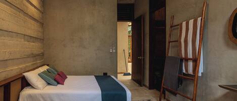 Quarto com duas camas, uma escada de madeira e uma porta que dá para outro cômodo.