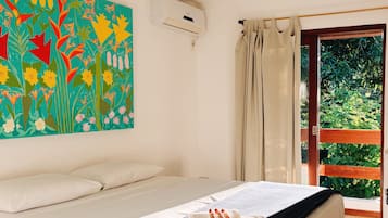 Quarto com cama, ventilador de teto, janela com cortinas e decoração de parede colorida.
