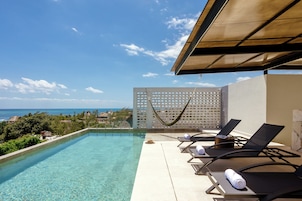 Piscina com água cristalina, vista para o oceano e espreguiçadeiras com toalhas.