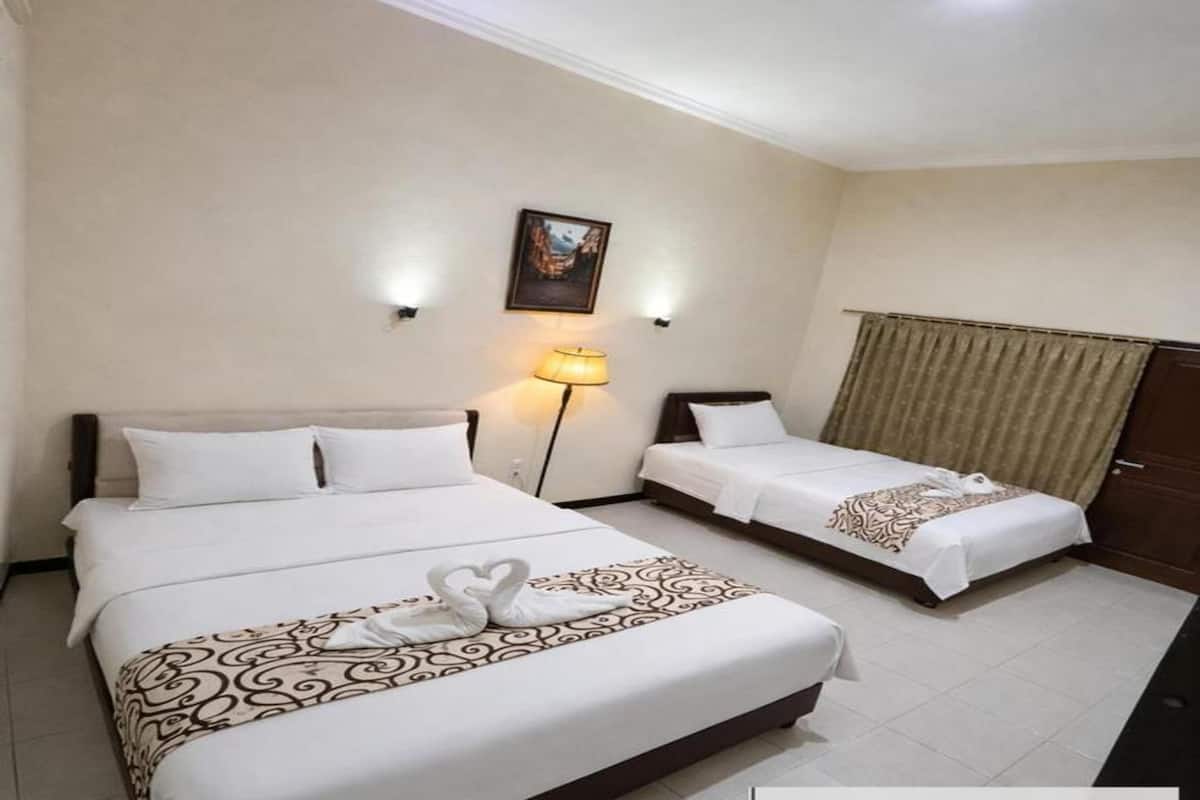 Quarto de hotel com duas camas, um quadro na parede, uma luminária e uma cortina.