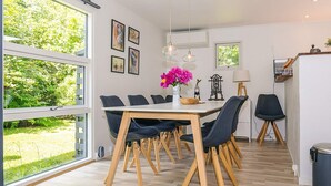 Uma sala de jantar moderna com mesa de madeira, cadeiras pretas e um vaso de flores.