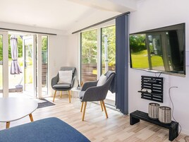 Uma sala de estar moderna com televisão, sofá, poltrona e mesa de jantar.