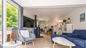 Uma sala de estar moderna com sofá, poltrona e área de jantar com mesa e cadeiras.