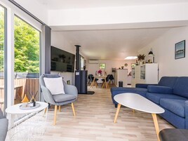 Uma sala de estar moderna com sofá, poltrona e área de jantar com mesa e cadeiras.