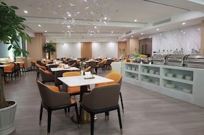 Uma sala de jantar moderna com mesas, cadeiras, um buffet e elementos decorativos pendentes.