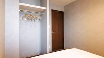 Quarto de hotel com cama, guarda-roupa de madeira e cabideiro com cabides.
