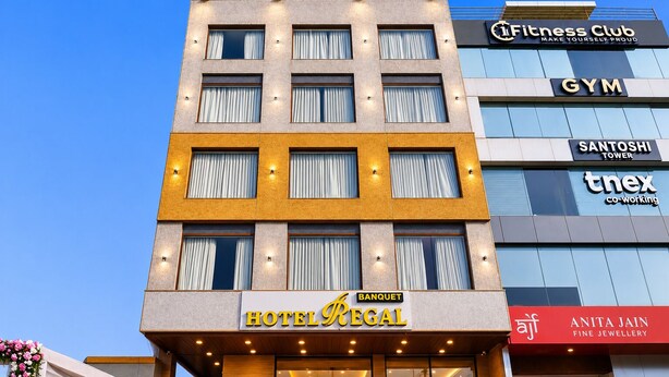 Um hotel com uma placa indicando 'HOTEL REGAL', um clube de fitness, uma academia e uma joalheria.