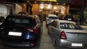 Entrada de hotel com placa indicando 'BANQUET HOTEL REGAL', carros estacionados em frente e uma placa de licença visível em um veículo.