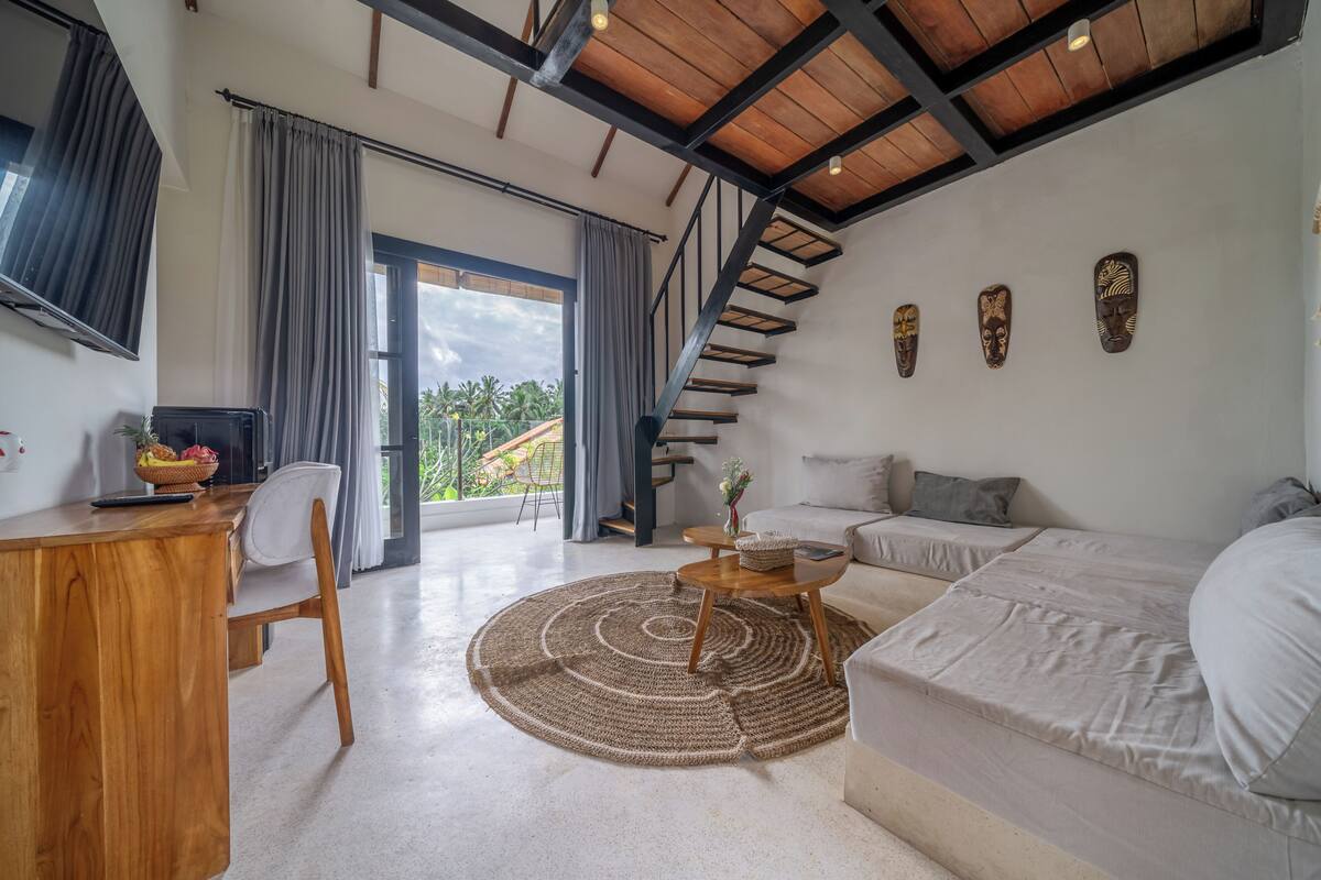 Uma sala de estar moderna com um sofá, um tapete redondo, uma escrivaninha de madeira e uma escada.