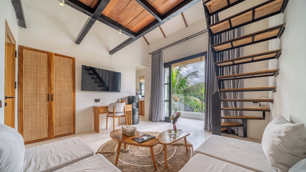 Quarto moderno com sofá, mesa de centro, televisão e escada.