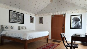 Quarto com cama, porta de madeira, escrivaninha e cadeira.