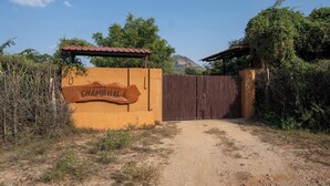 Uma trilha de terra que leva a um portão com uma placa que diz 'SHAMBHALA'.