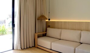 Quarto moderno com sofá, cortinas e luminária pendente.