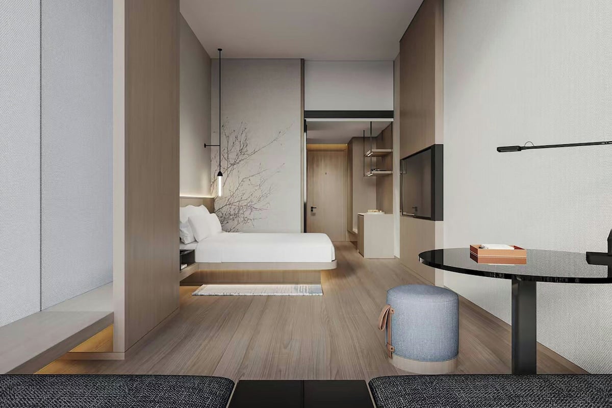 Quarto de hotel moderno com uma cama, uma escrivaninha, uma cadeira, uma TV e uma pequena mesa.