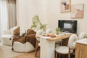 Uma sala de estar moderna com um sofá, uma mesa de jantar de madeira e uma televisão.