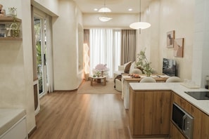 Uma cozinha moderna com armários de madeira, uma área de jantar com mesa e cadeiras, e uma sala de estar com sofá e cortinas.