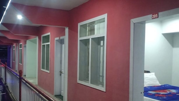 Um corredor com parede vermelha, portas brancas e placa indicando o número 205.